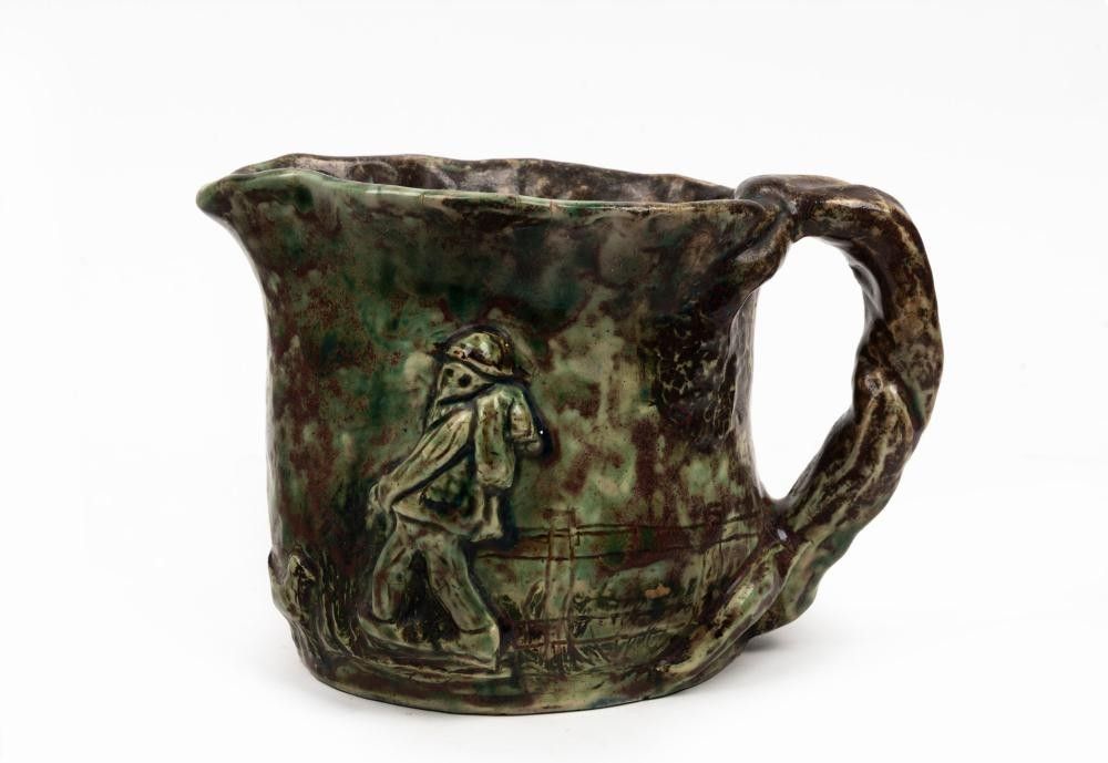 Green glazed hand-built pottery jug with applied figures in landscape ...